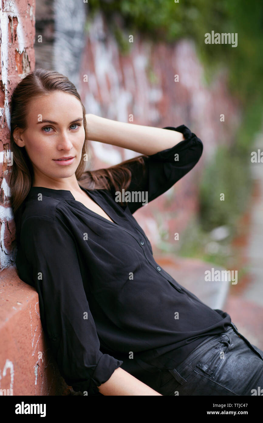 Portrait of woman leaning on wall Stock Photo - Alamy