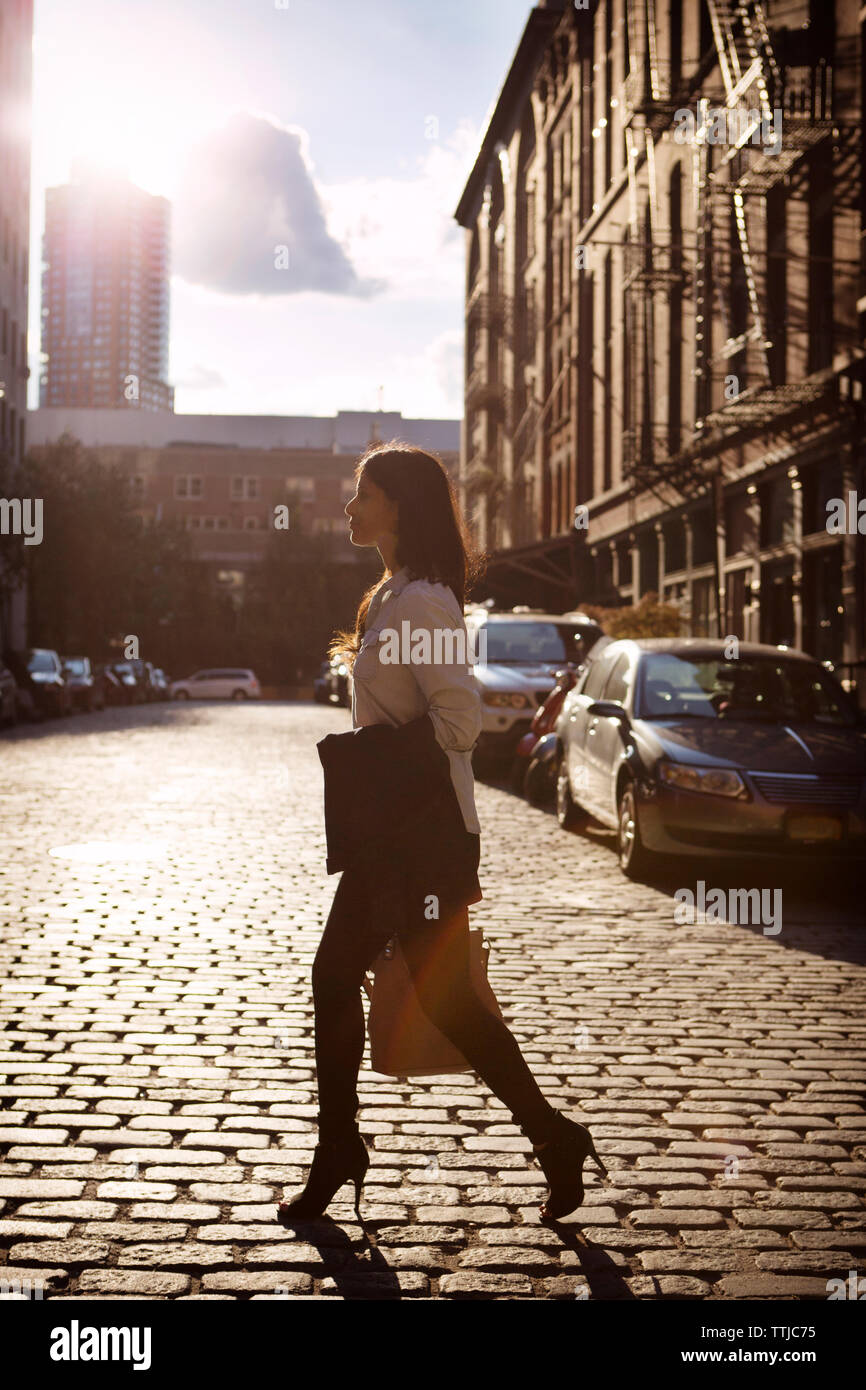 Side view of woman walking on city street Stock Photo - Alamy