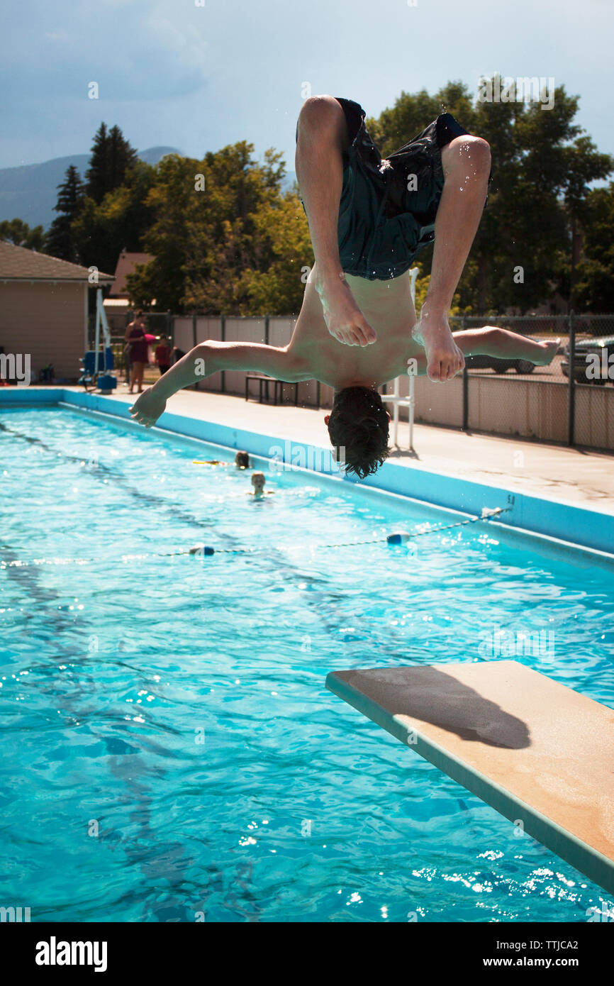 Rear view of teenage boy jumping in swimming pool Stock Photo - Alamy