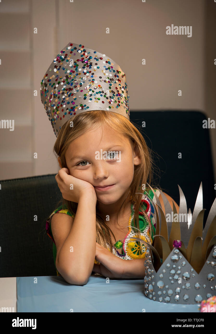 Portrait of girl wearing crown sitting by table home Stock Photo - Alamy