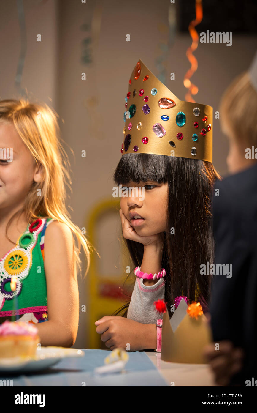 Girl with hand on chin looking at cup cake during birthday party Stock ...