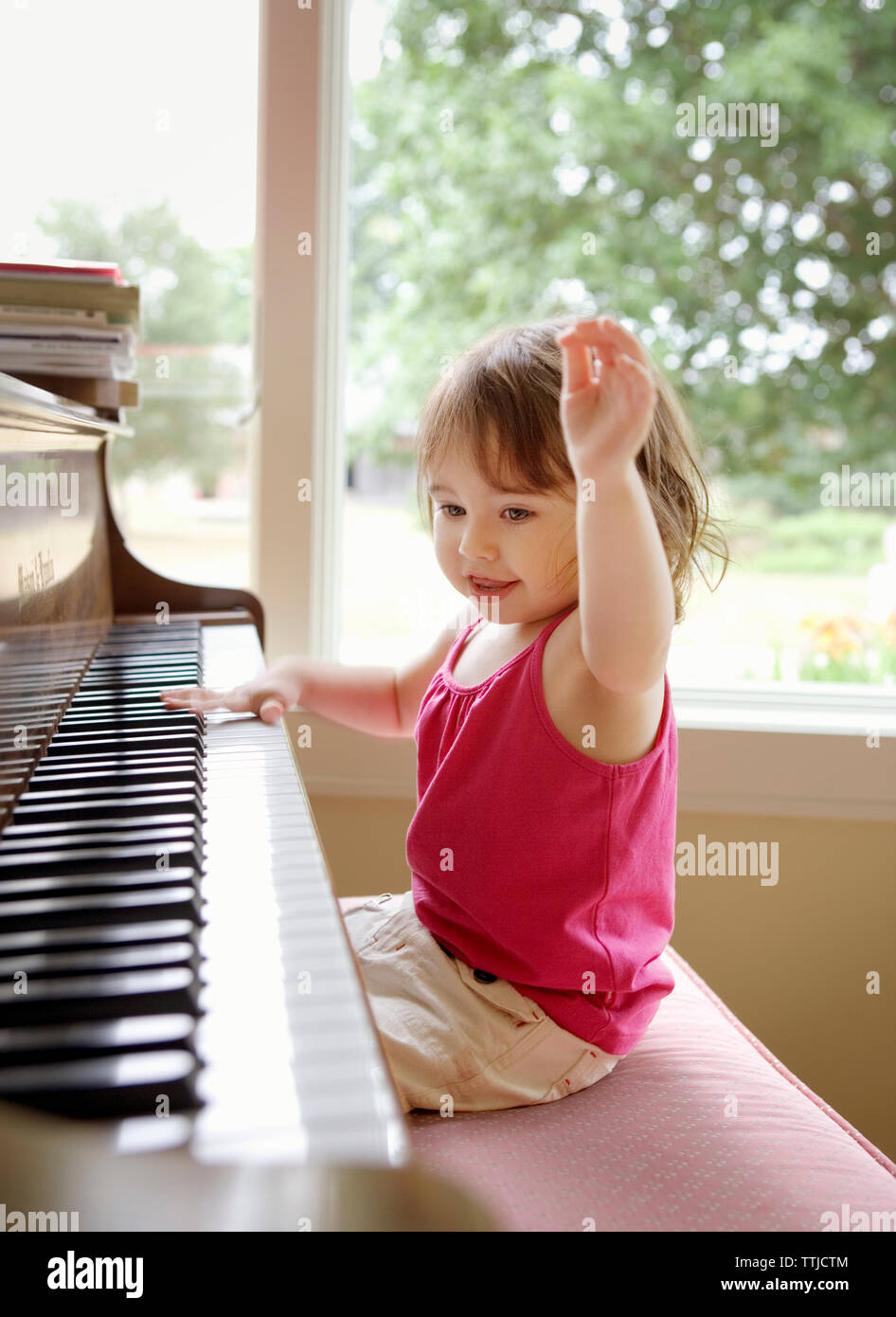 Side view of cute girl playing piano Stock Photo - Alamy