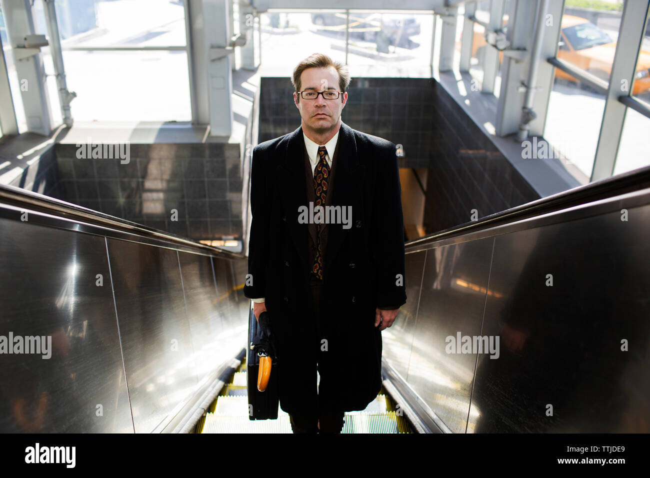 Portrait of businessman standing on escalator Stock Photo - Alamy