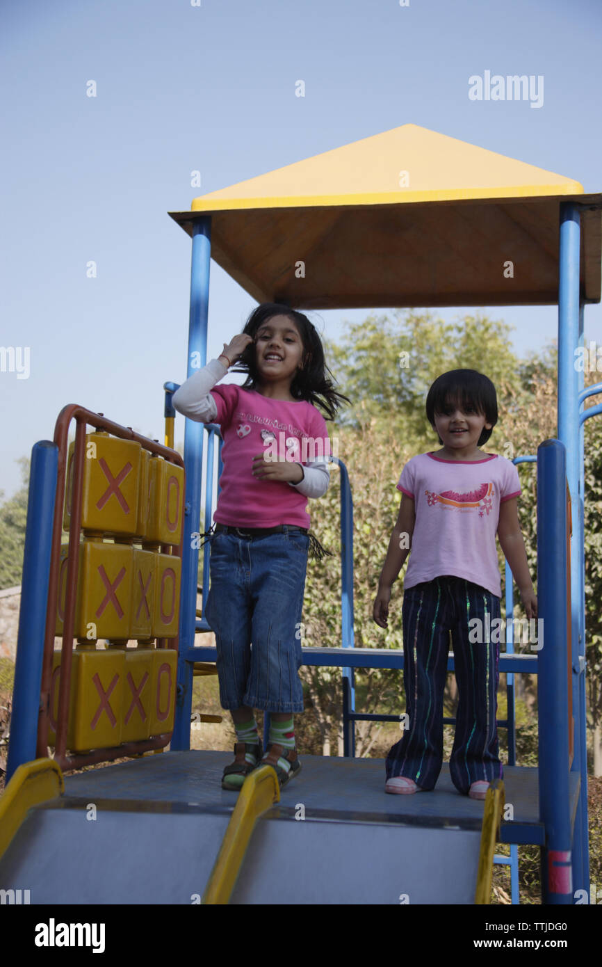 Two Indian girls standing on slide platform Stock Photo - Alamy