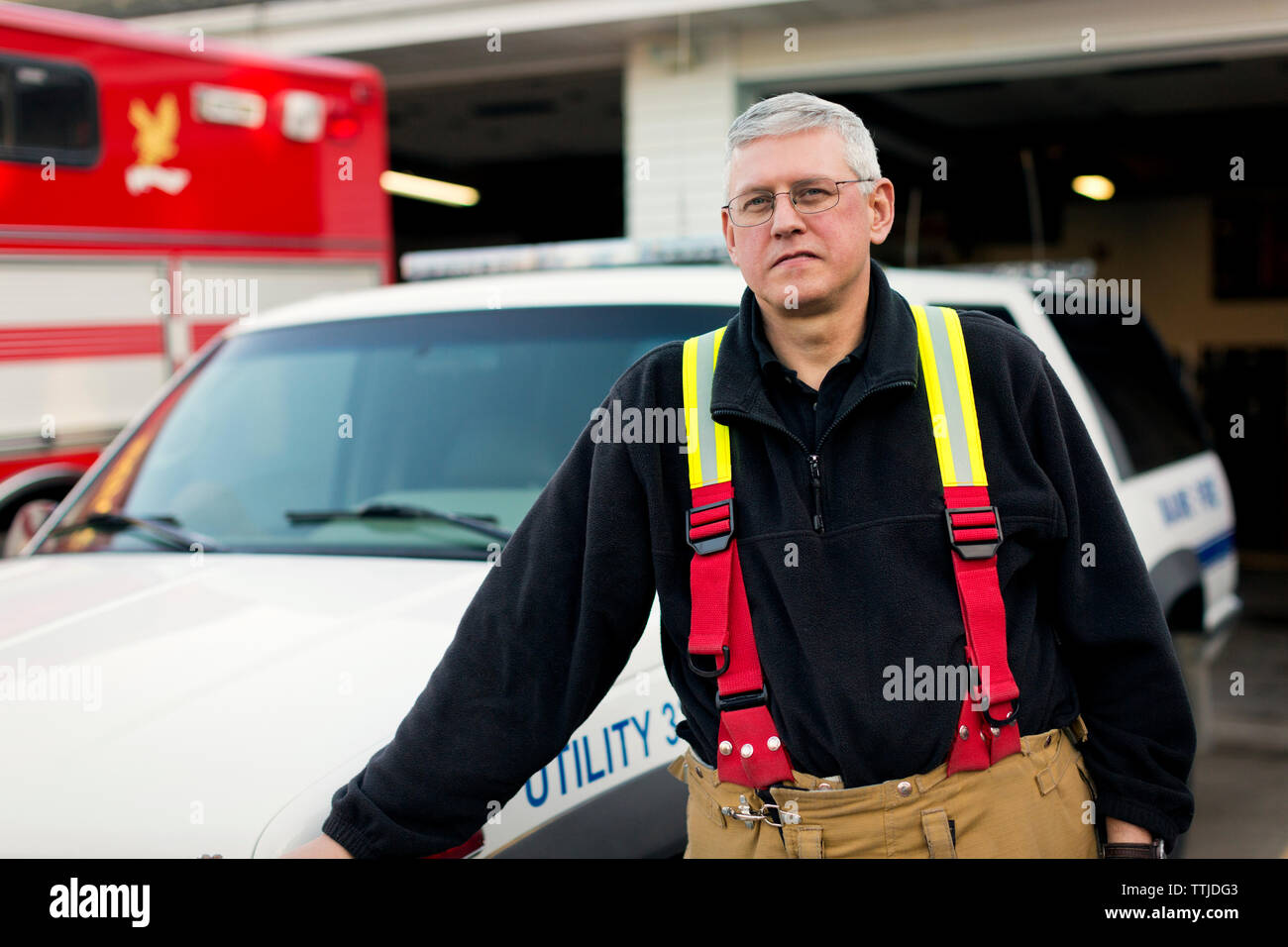 Portrait of firefighter leaning on car at fire station Stock Photo - Alamy