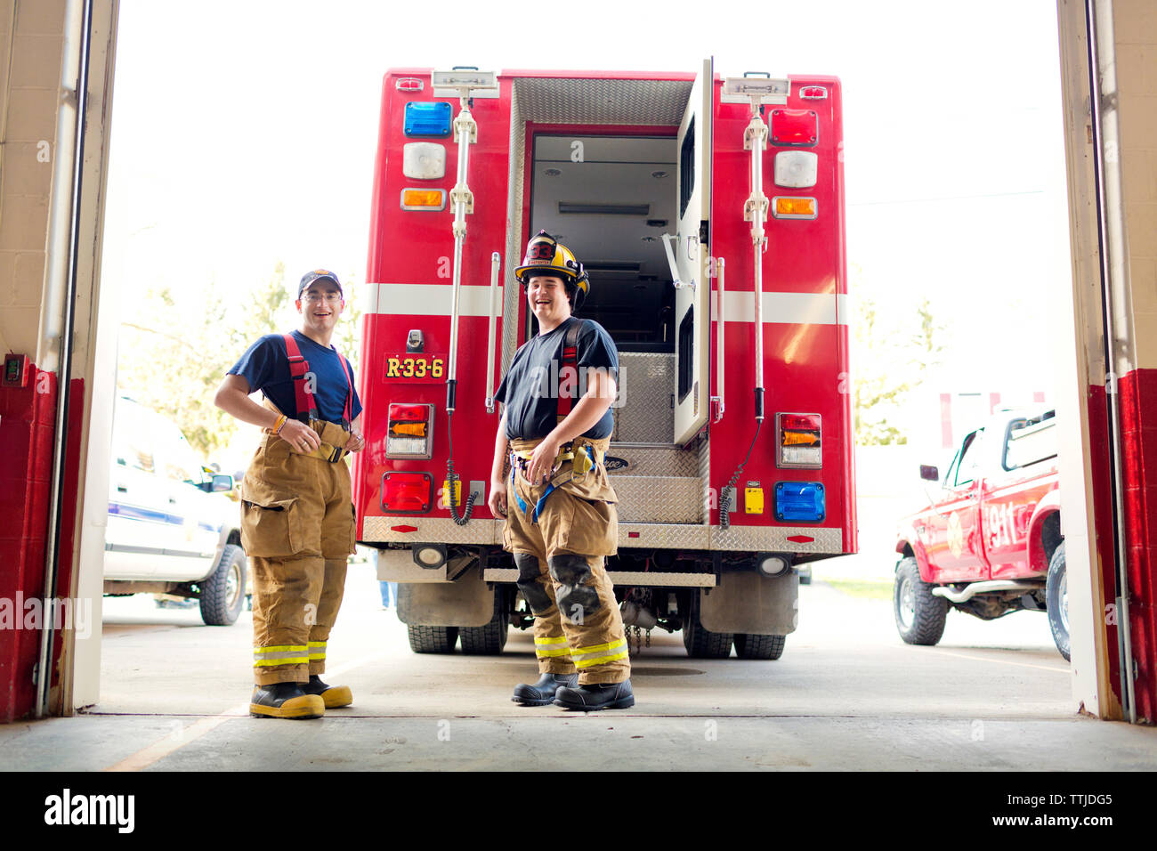 Portrait of happy fire fighters standing against fire engine Stock ...
