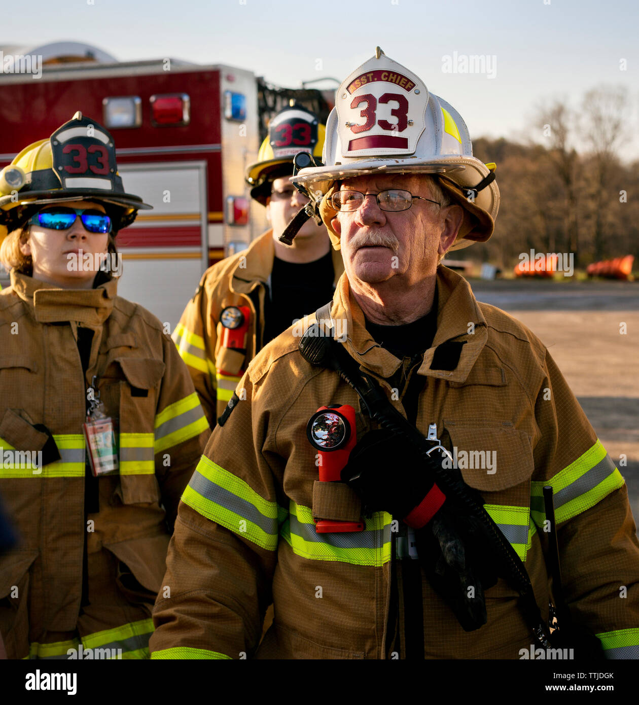 Firefighter looking away while standing with coworkers at fire station ...
