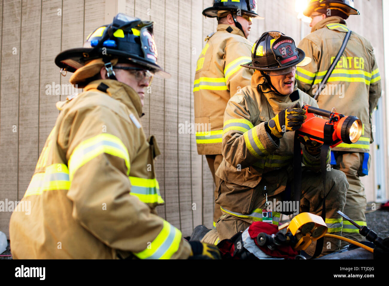 Firefighter holding flashlight while coworkers working at field Stock ...