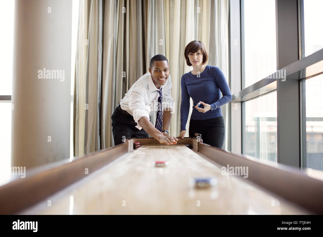 Colleagues playing shuffleboard in office Stock Photo - Alamy