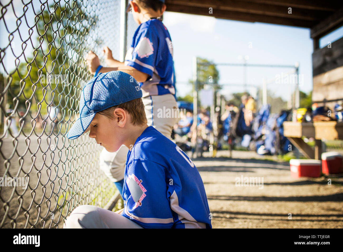 Side view of boy crouching in dugout on sunny day Stock Photo - Alamy
