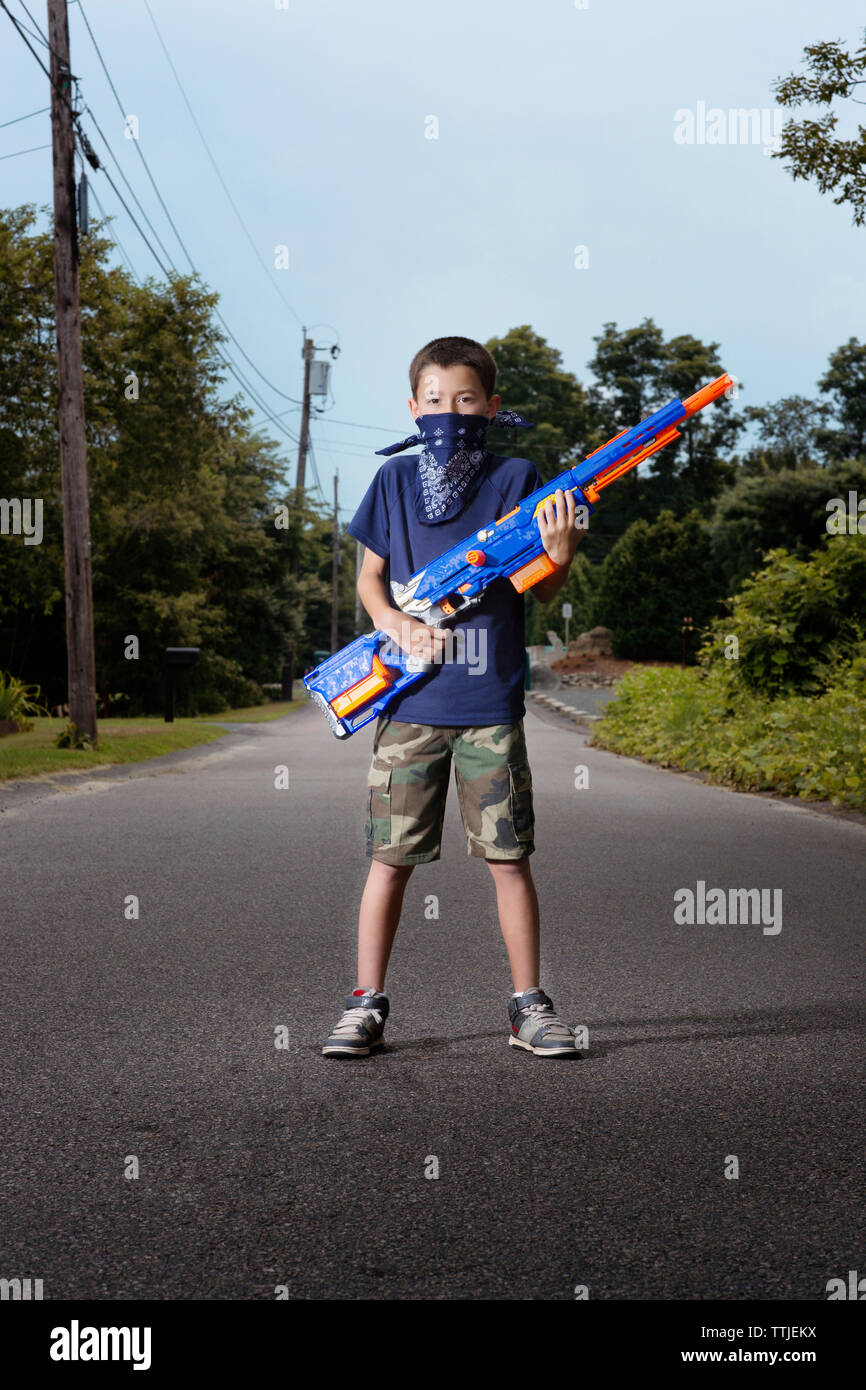 Portrait of boy with toy gun standing on footpath against sky Stock ...