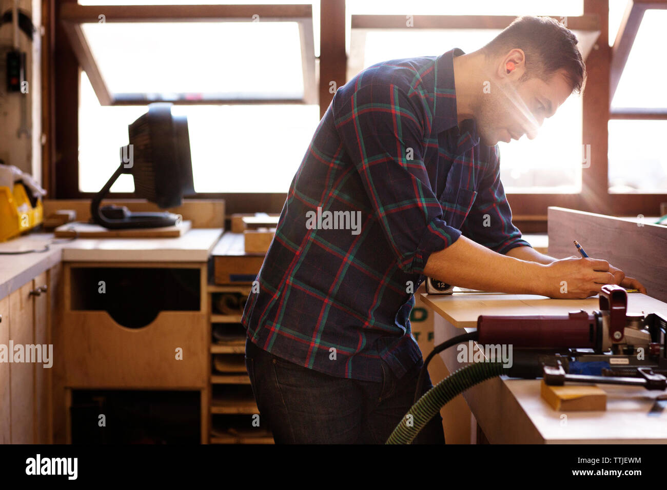 worker measuring wood while working in carpentry workshop Stock Photo ...