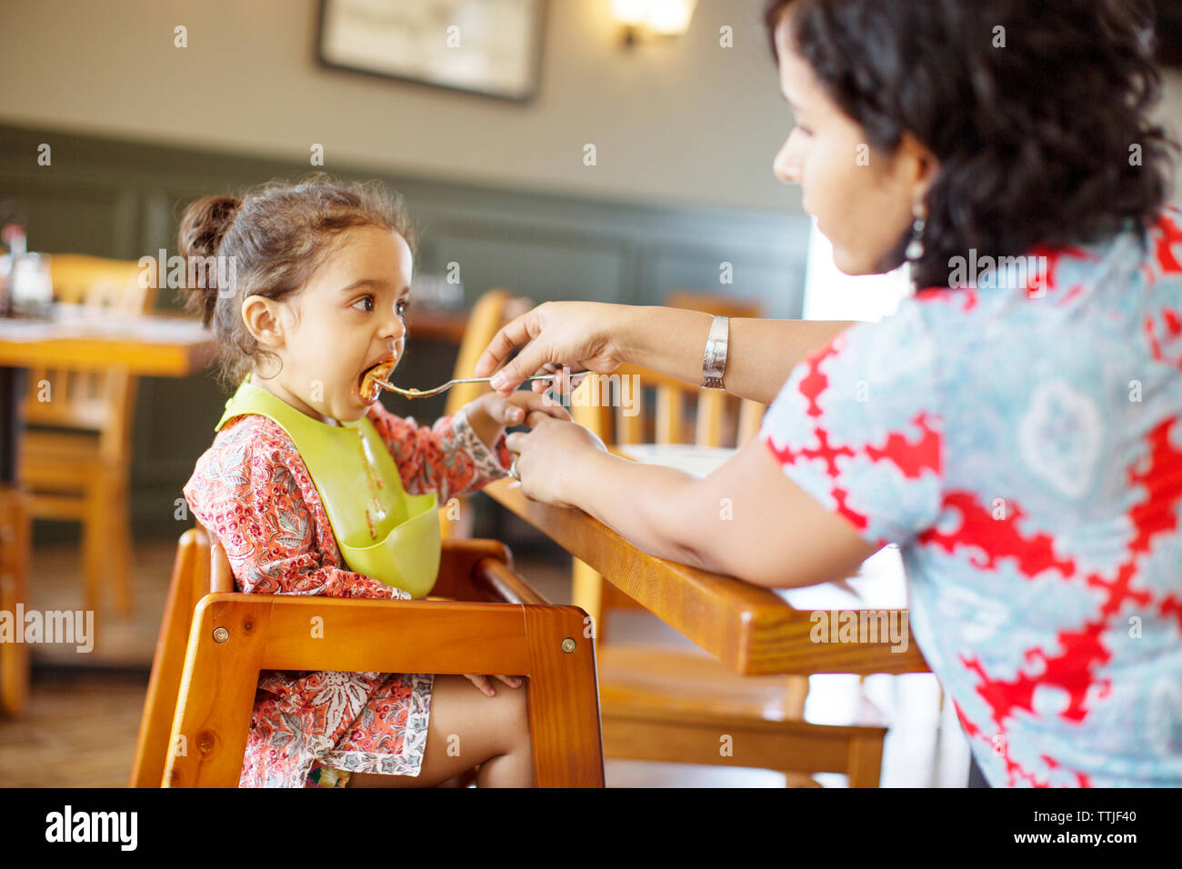 Mother feeding daughter at restaurant Stock Photo - Alamy