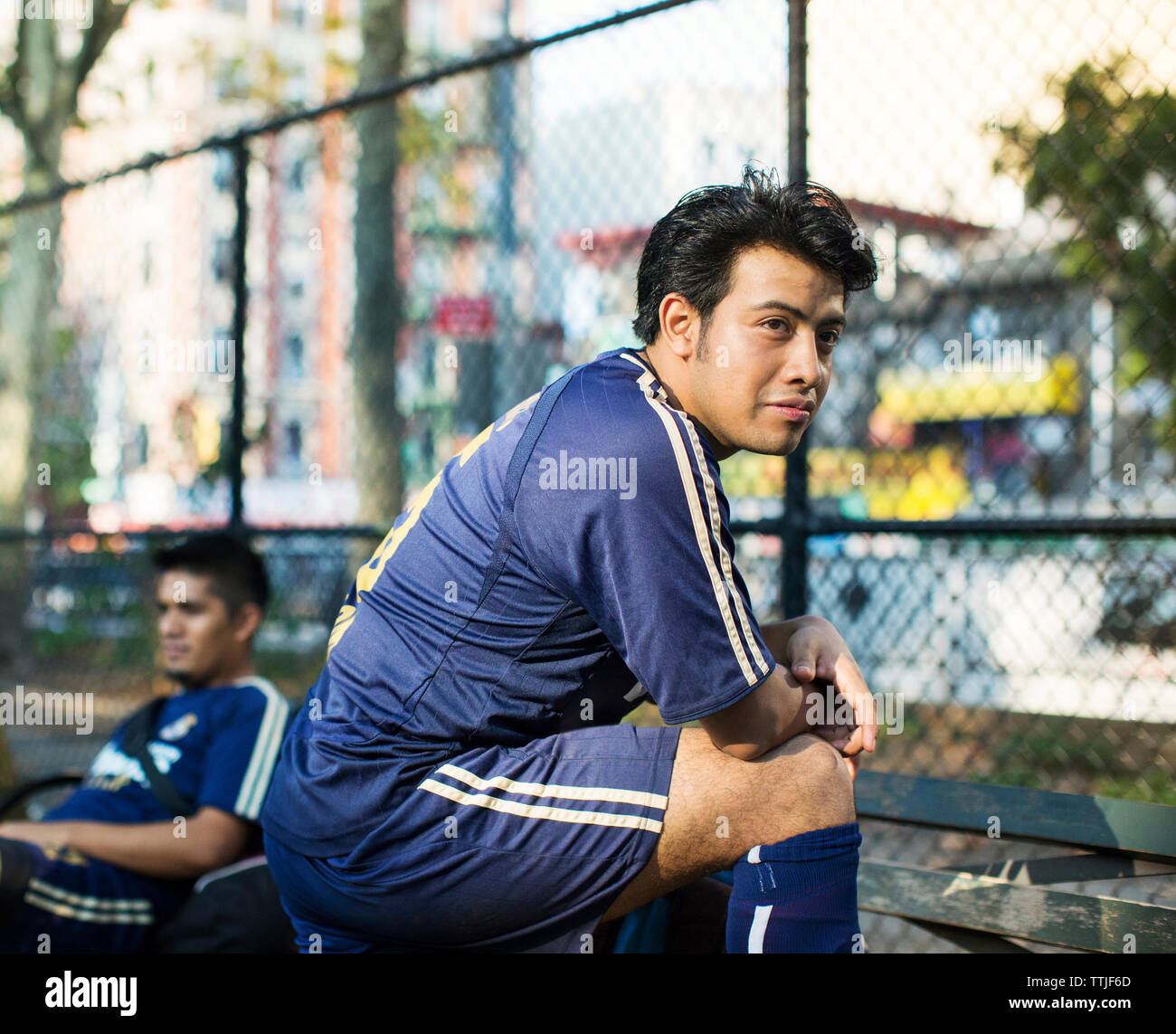 Man looking away while leaning on bench at soccer field Stock Photo - Alamy