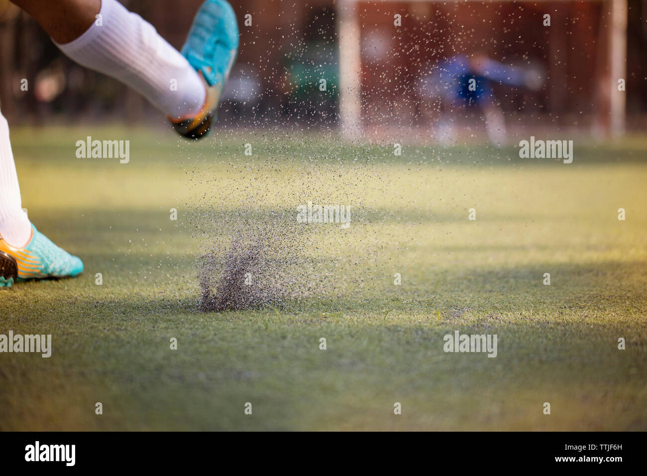 Cropped image player kicking ball at soccer field Stock Photo - Alamy