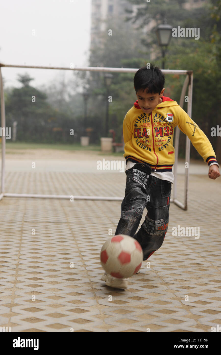 Boy playing football in a back yard Stock Photo - Alamy