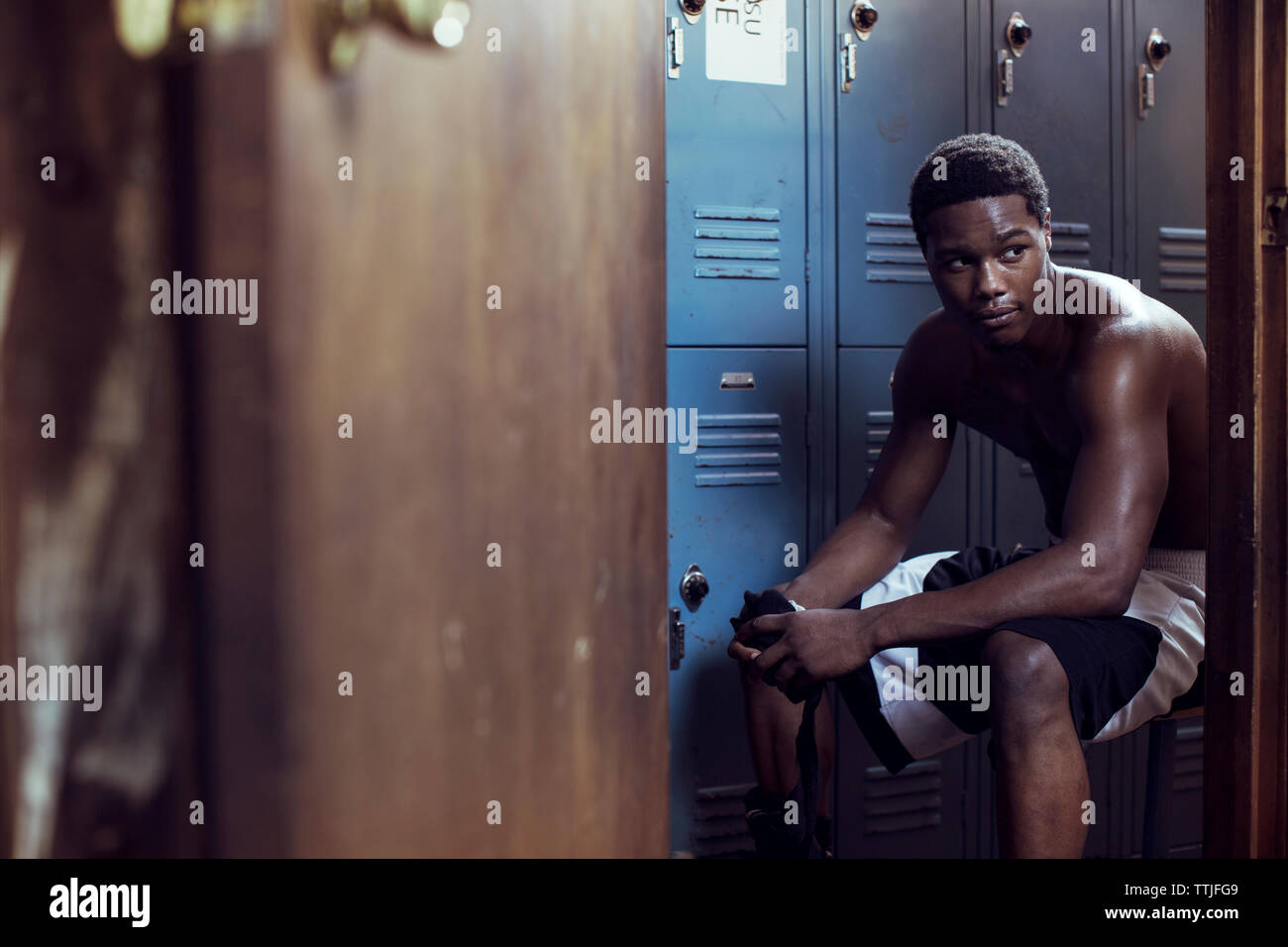 Boxer looking away while sitting in locker room Stock Photo - Alamy