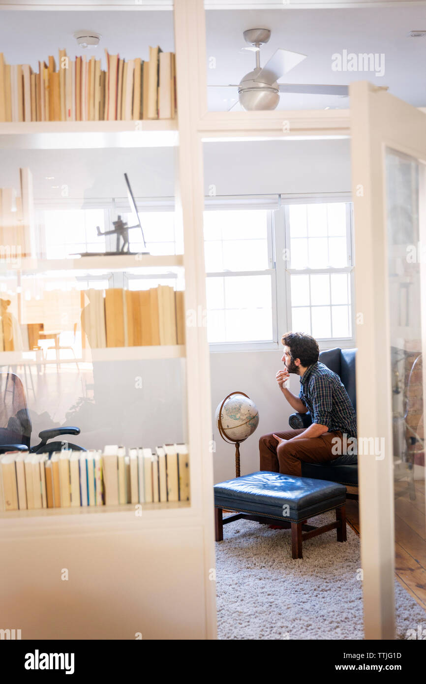 Thoughtful man sitting in library at home Stock Photo - Alamy