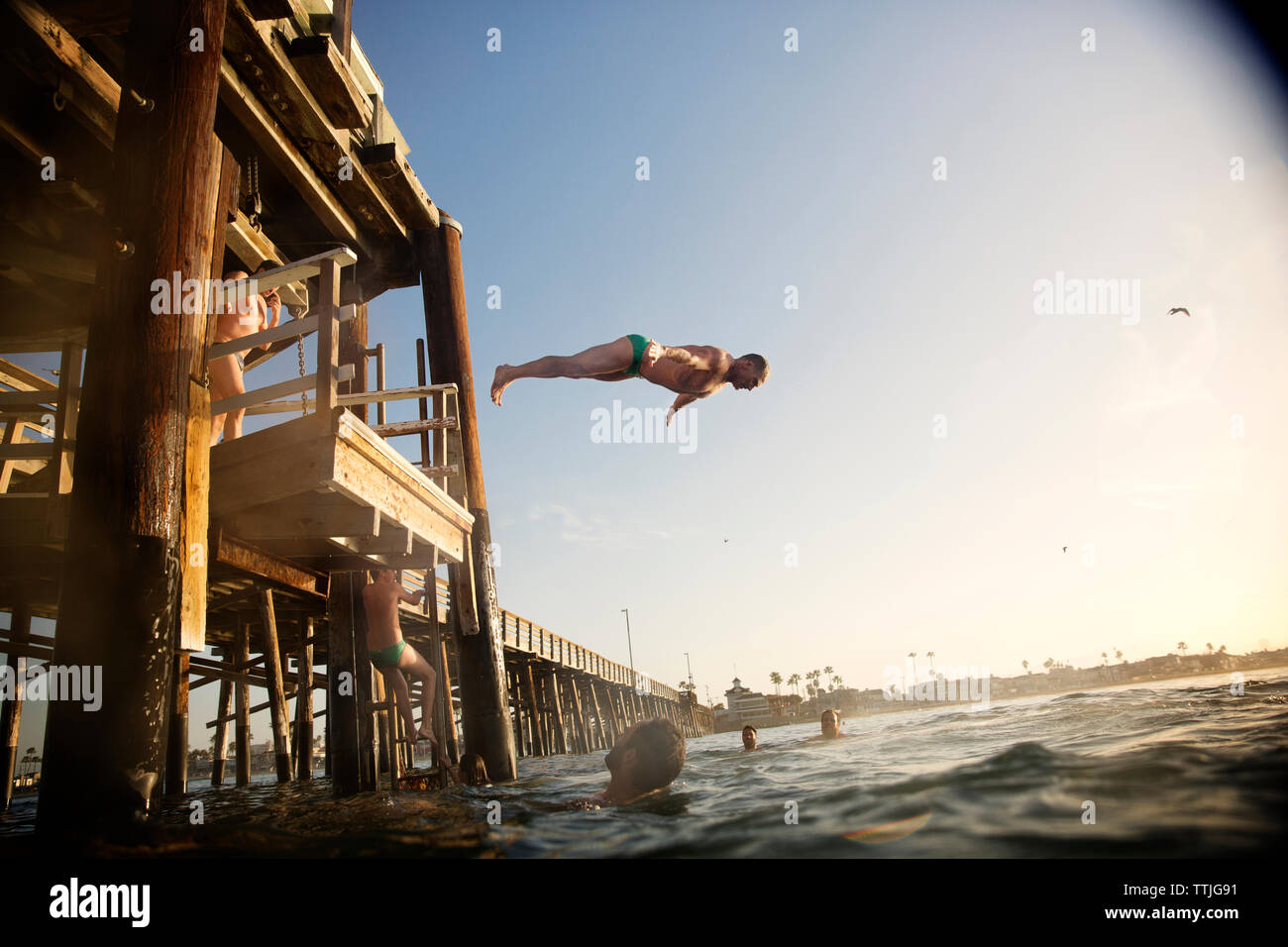 Friends jumping from pier in sea Stock Photo - Alamy