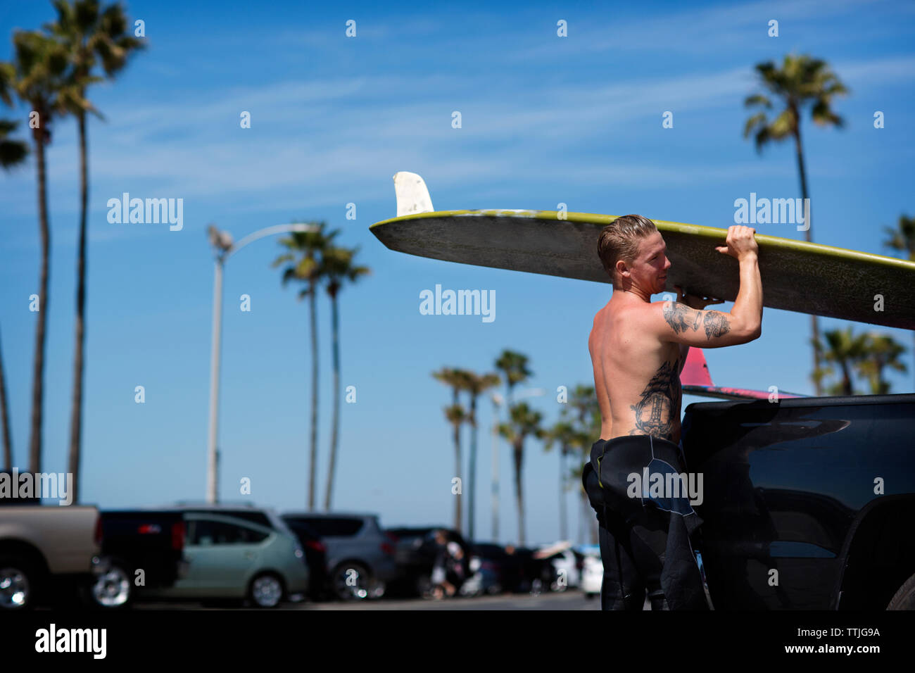 Side view of man carrying surfboard at beach Stock Photo - Alamy