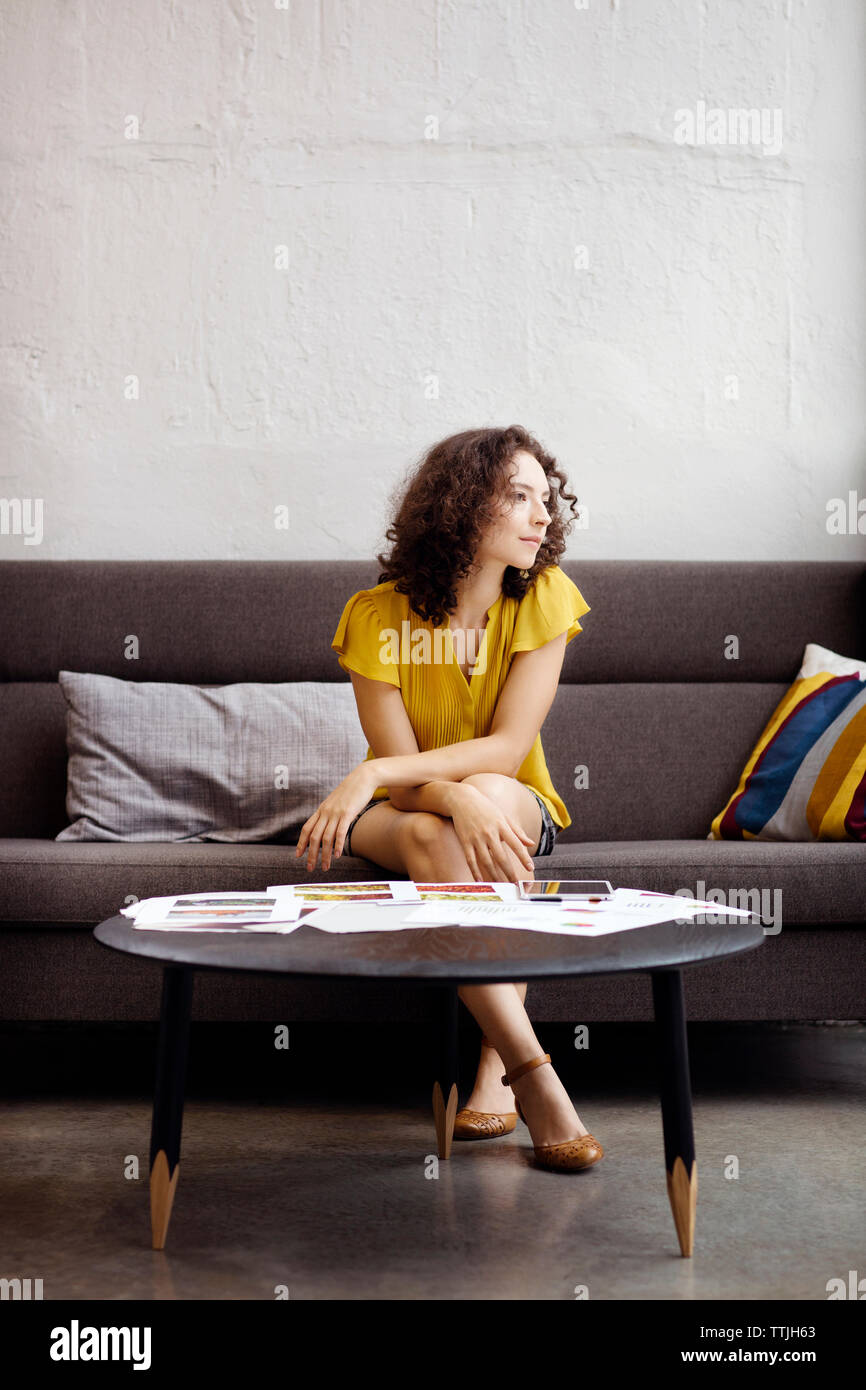 businesswoman looking away while sitting on sofa in office Stock Photo ...