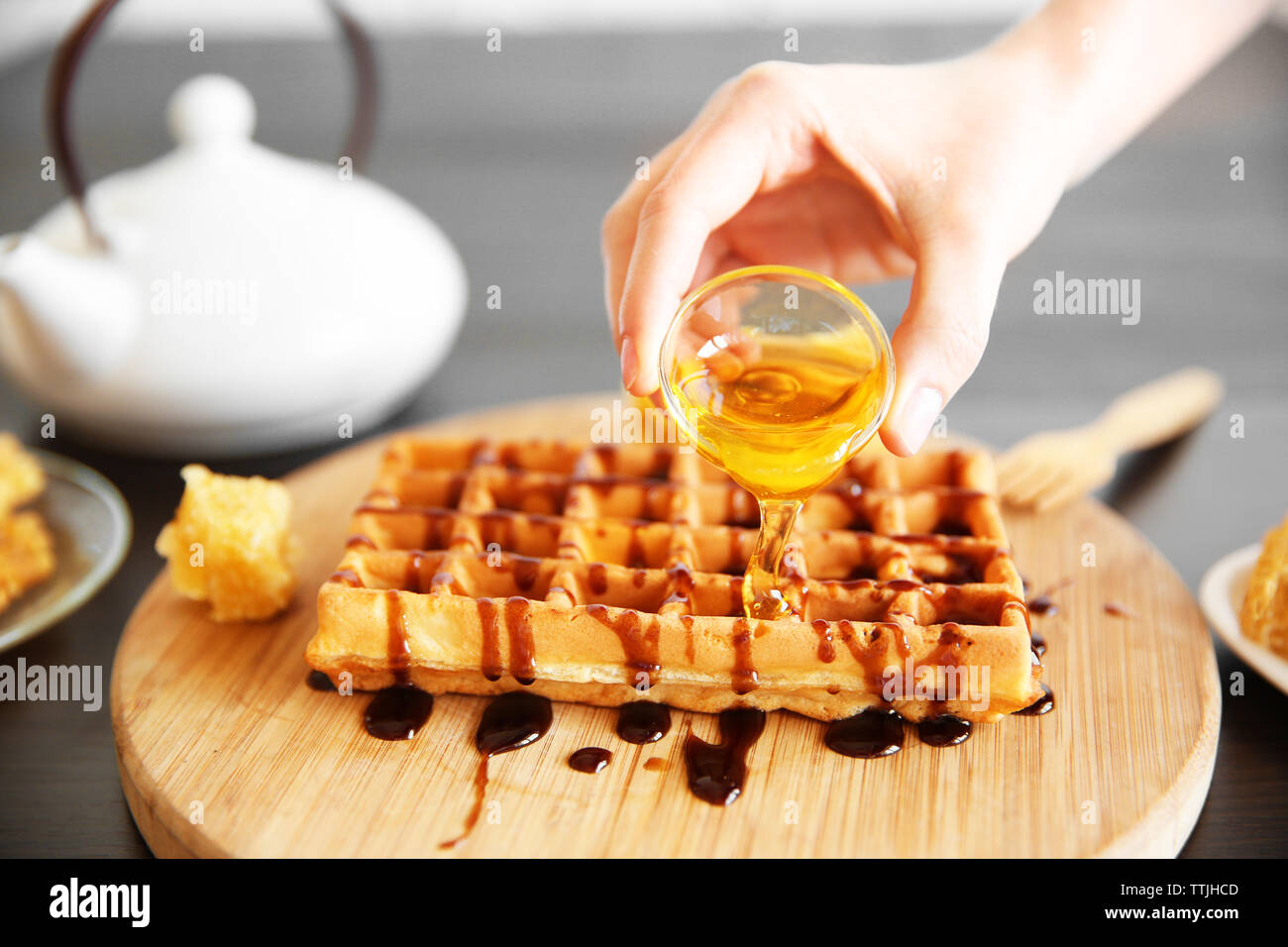 Female hand pouring honey on waffles Stock Photo - Alamy