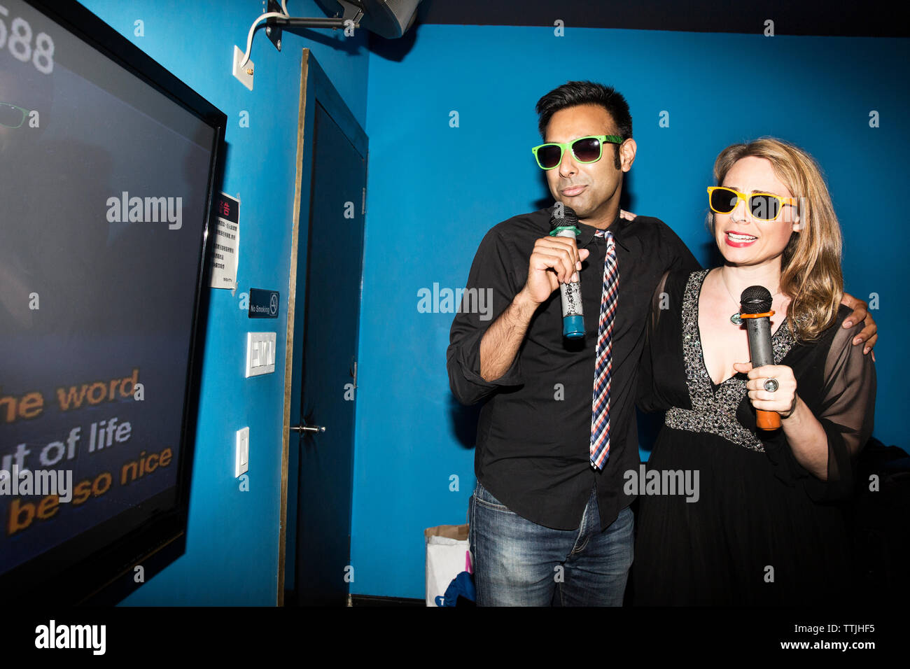 Happy couple singing karaoke while standing in nightclub Stock Photo ...