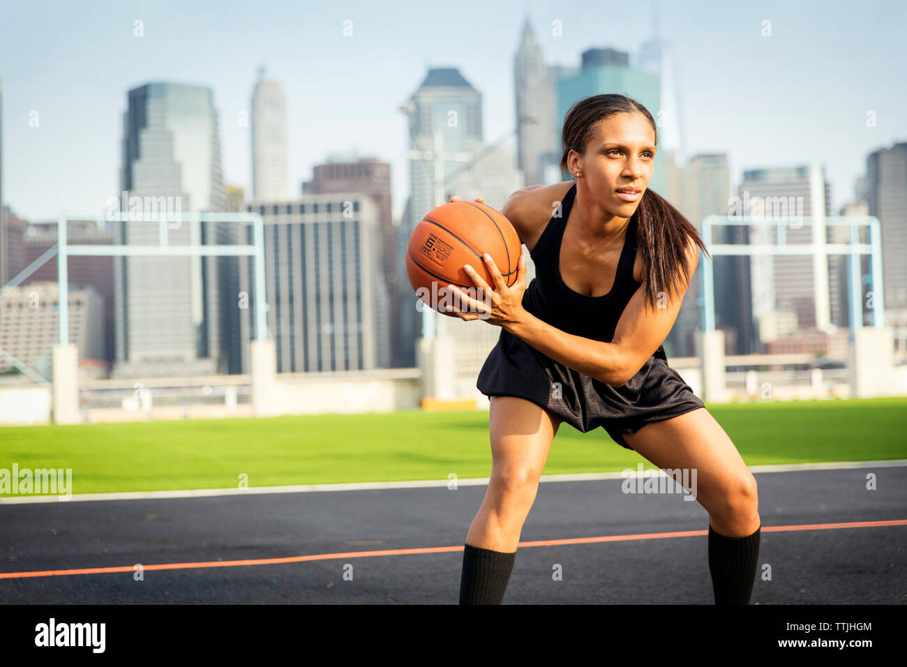 Woman playing basketball in court against buildings Stock Photo - Alamy