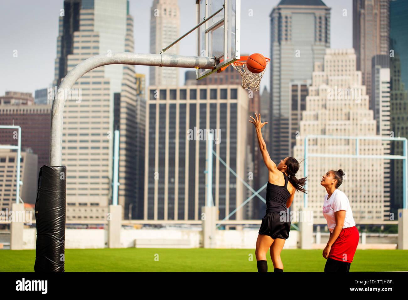 Woman scoring while playing basketball with friend in court against ...