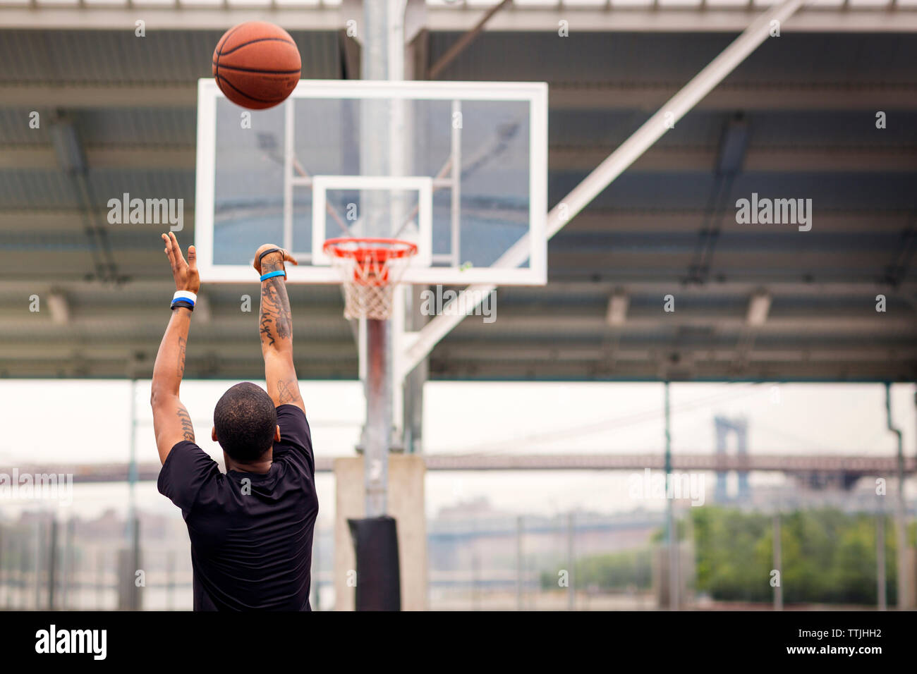 Rear view of man scoring while practicing basketball in court Stock ...