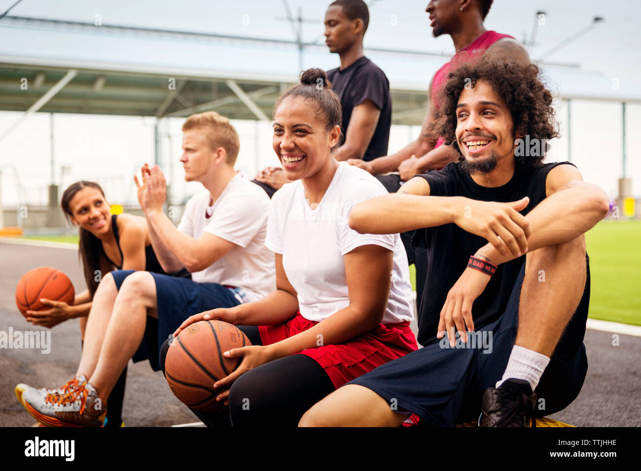 Happy athletes relaxing on bench in court Stock Photo - Alamy