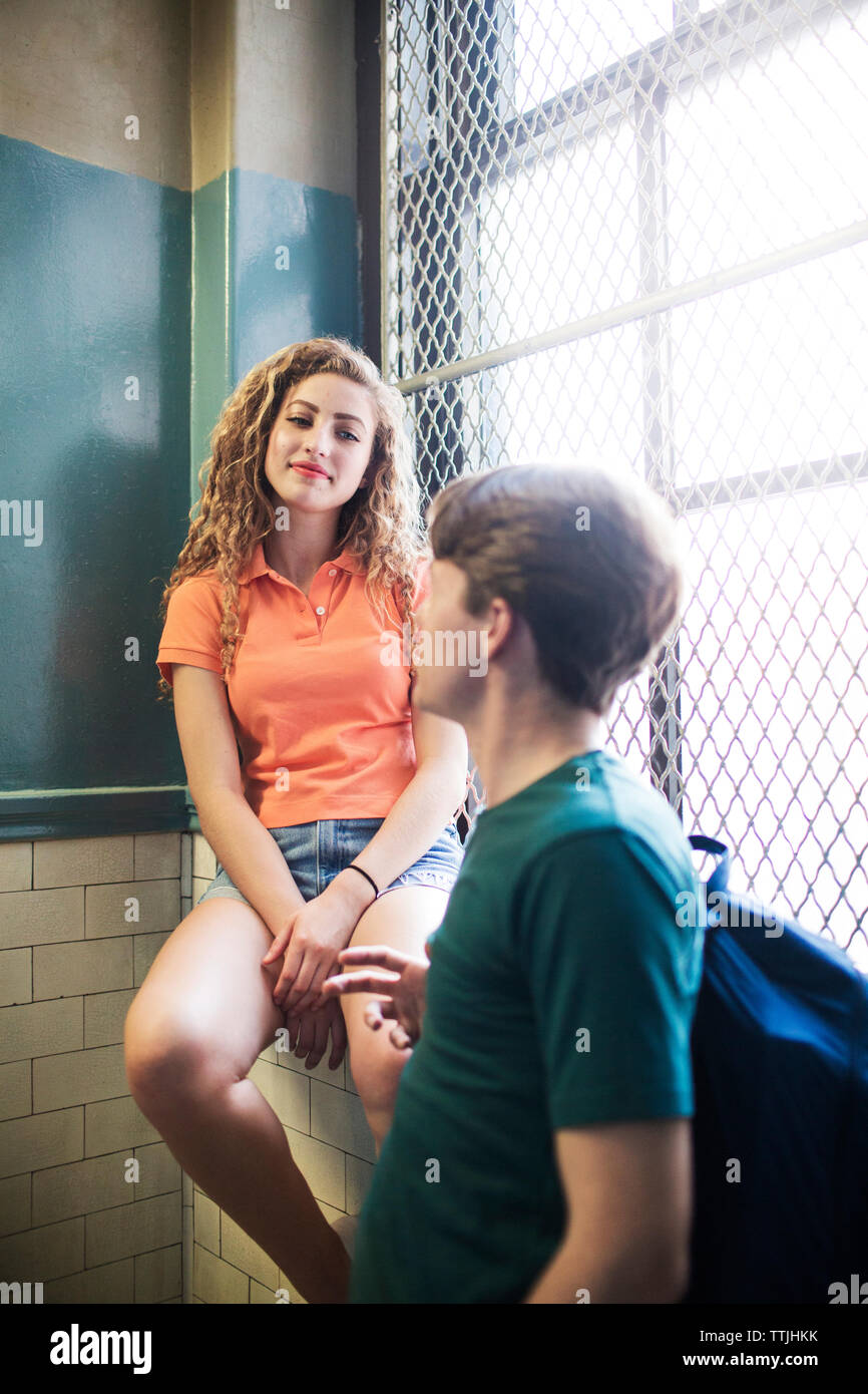 Woman sitting on window sill looking at man standing in corridor Stock ...