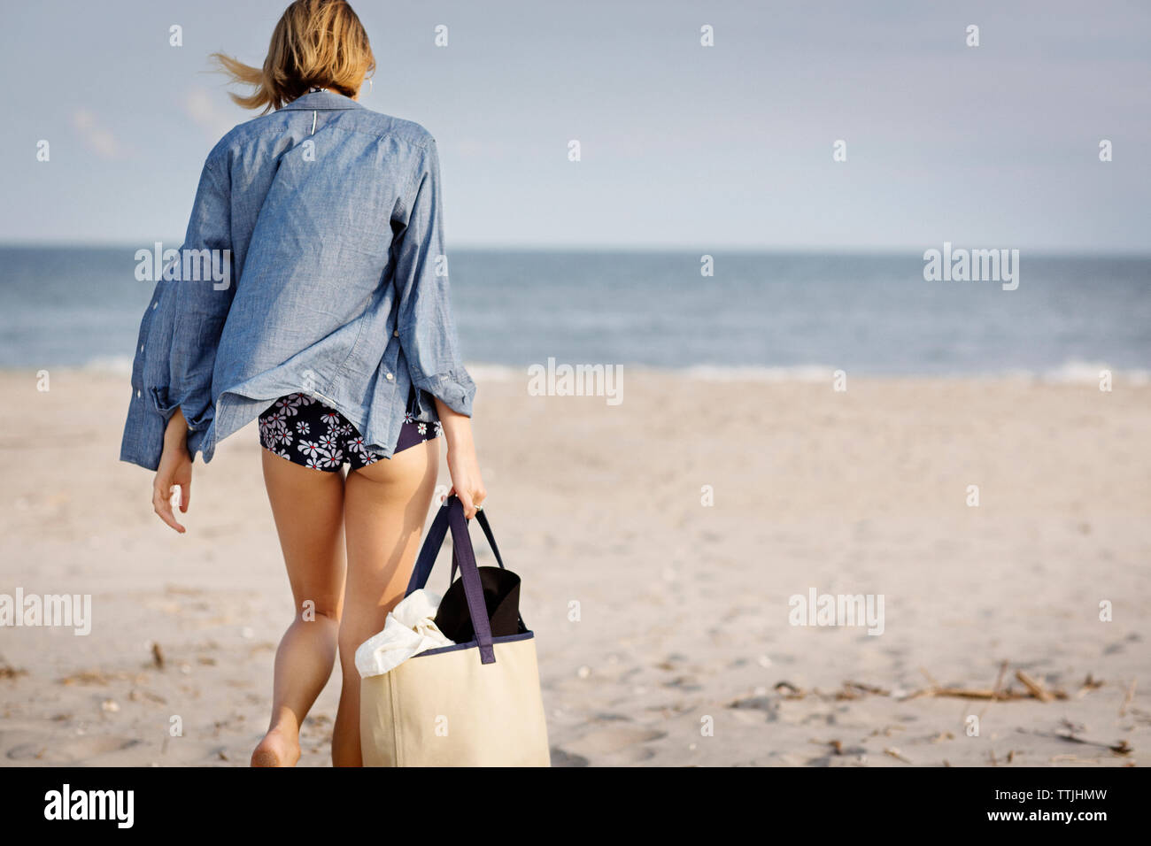 Rear view of woman walking on sand at beach Stock Photo - Alamy