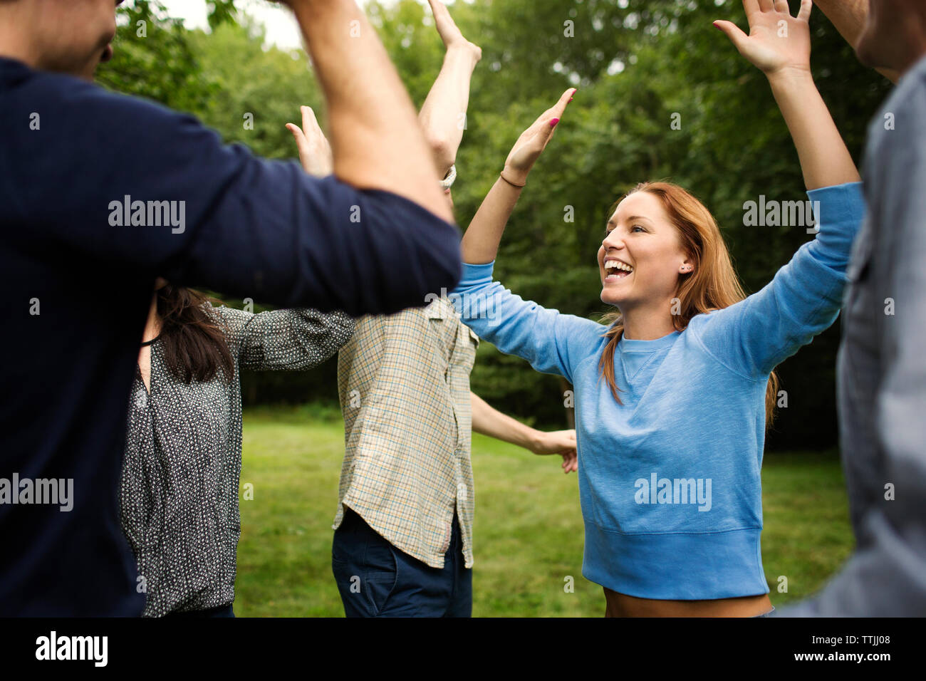 Happy friends high fiving while standing in field Stock Photo - Alamy