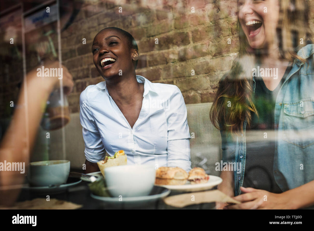 Happy friends sitting in cafe seen through window Stock Photo - Alamy