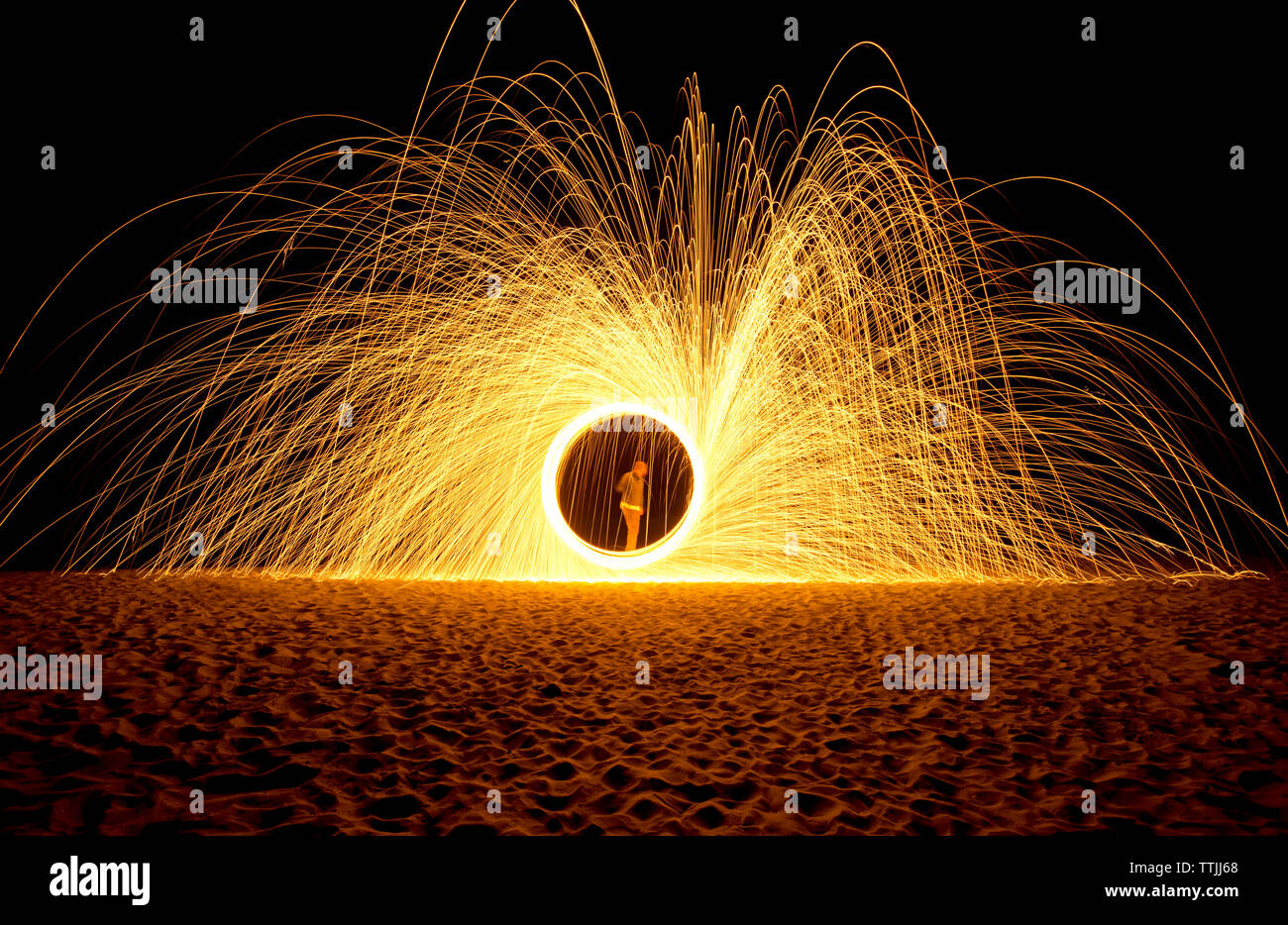 Man spinning wire wool while standing at beach Stock Photo - Alamy