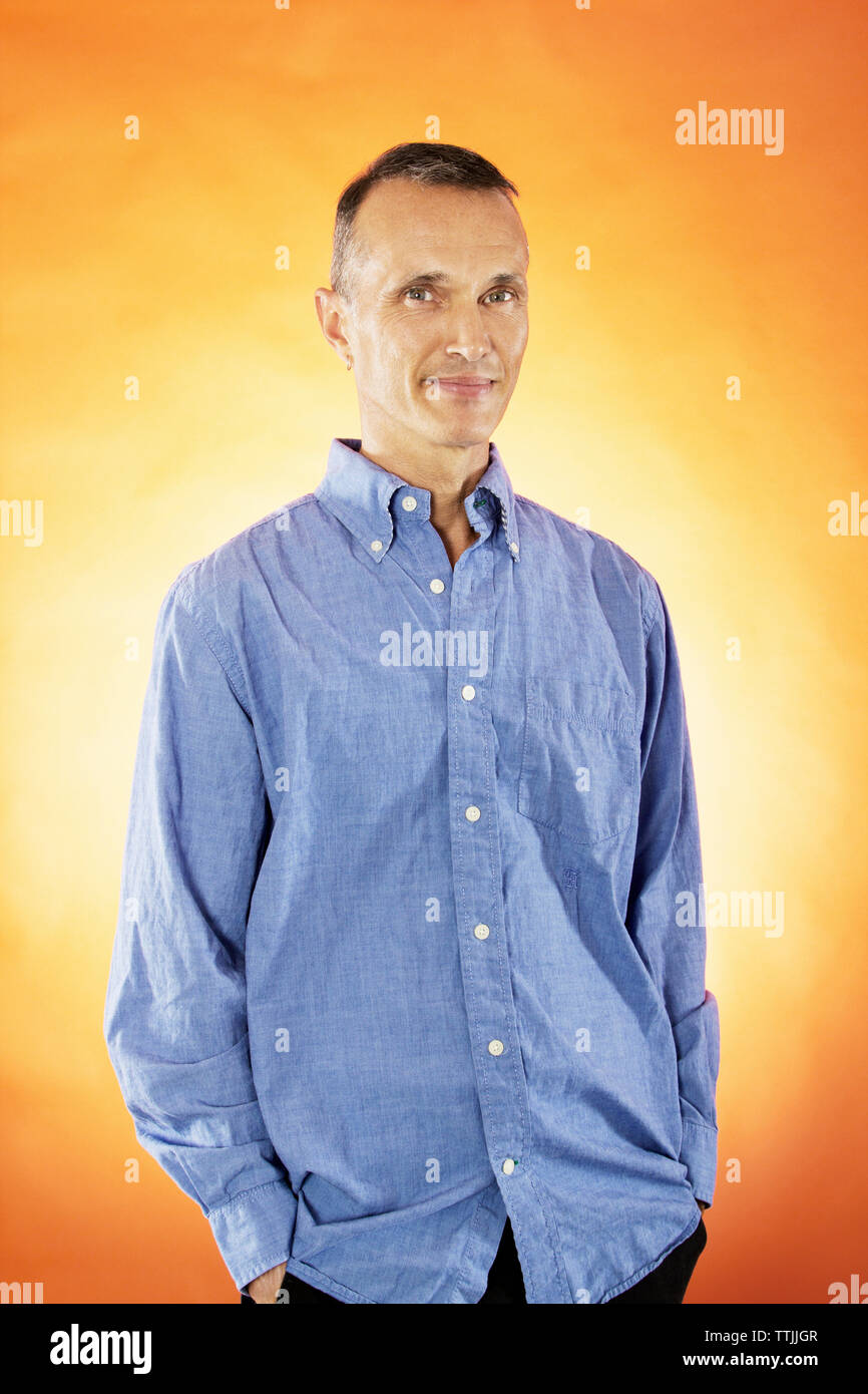 Portrait of man standing against orange background Stock Photo - Alamy