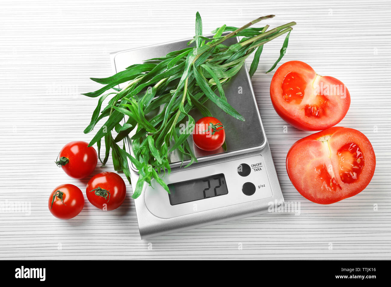Tomatoes and tarragon with digital kitchen scales on wooden background ...