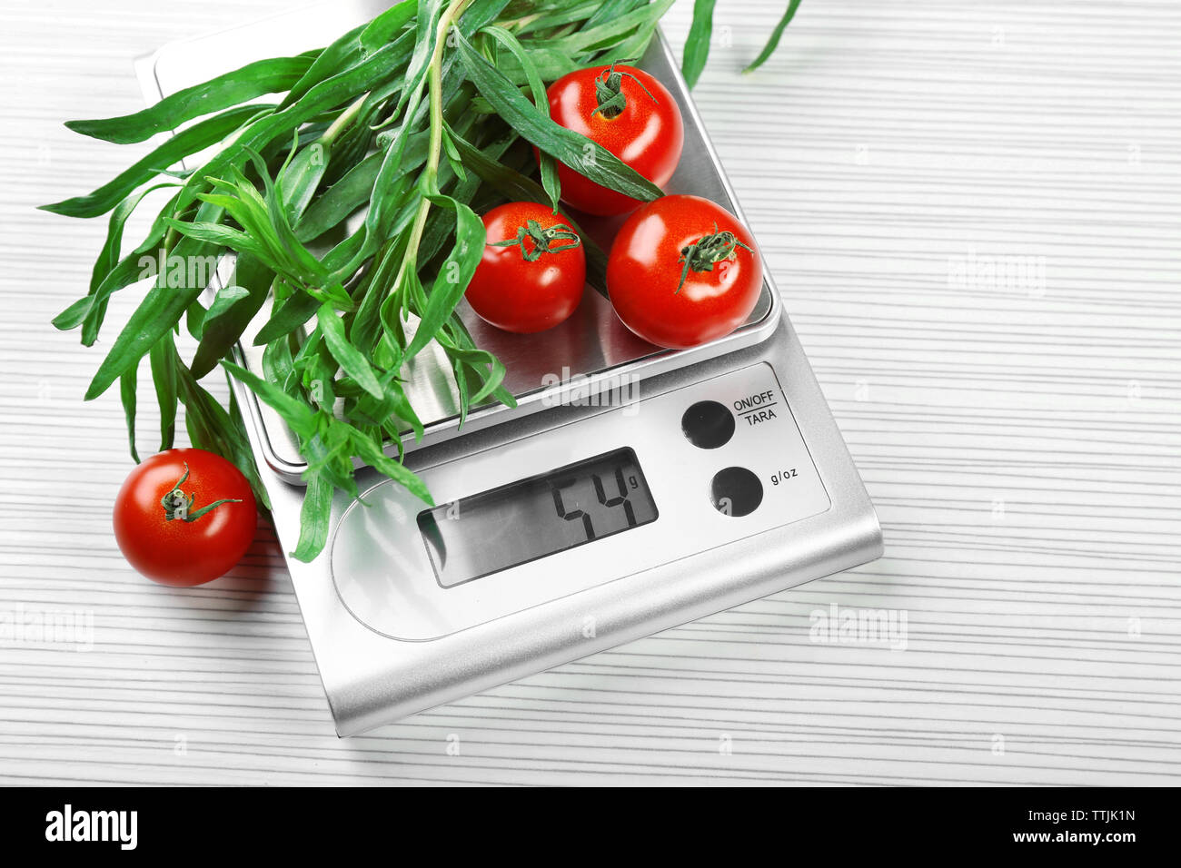 Tomatoes and tarragon with digital kitchen scales on wooden background ...