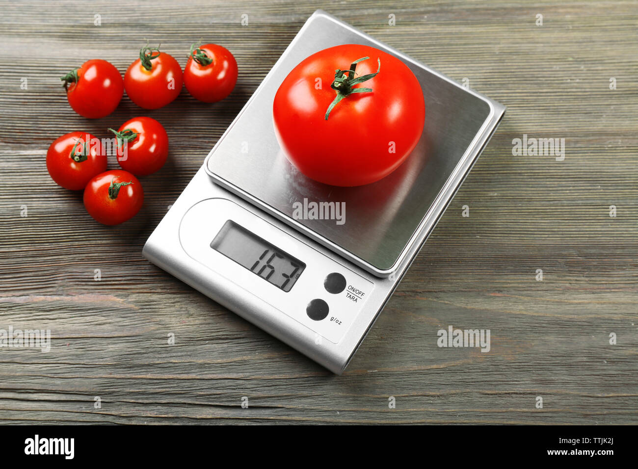 Tomatoes with digital kitchen scales on wooden background Stock Photo ...