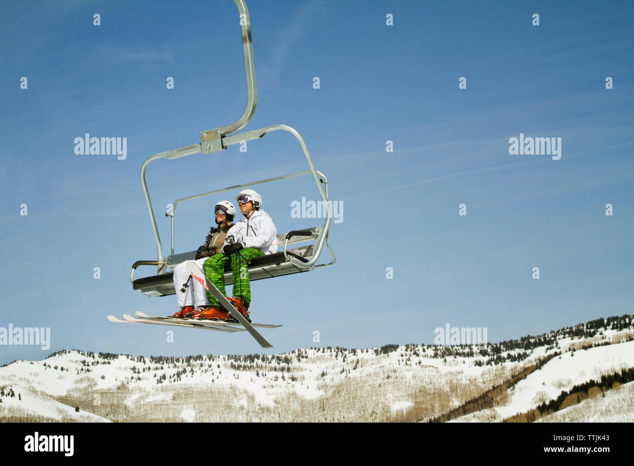 Skiers sitting in ski lift against clear sky Stock Photo - Alamy