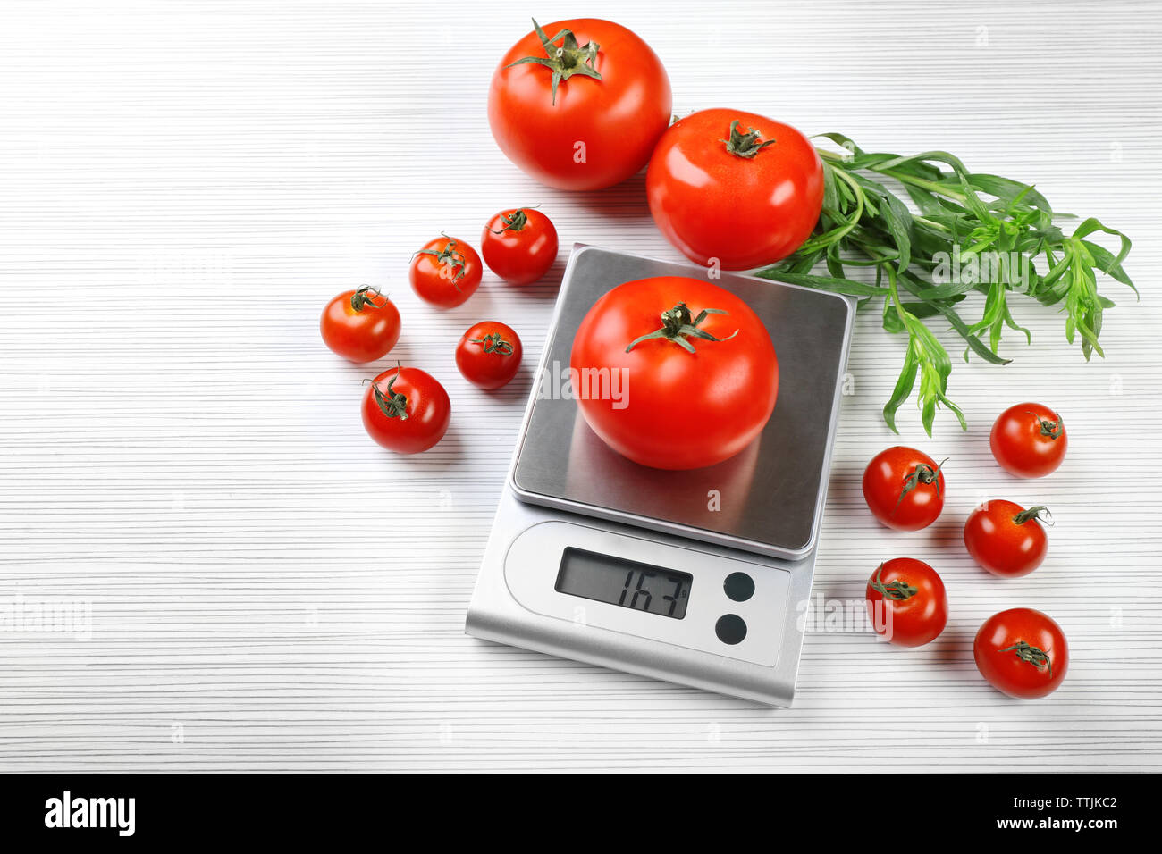 Tomatoes with digital kitchen scales on wooden background Stock Photo ...
