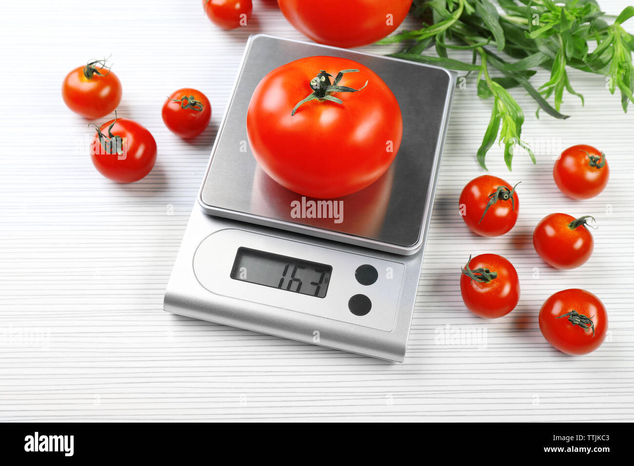 Tomatoes with digital kitchen scales on wooden background Stock Photo ...