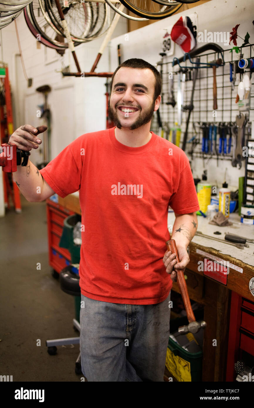 Portrait of man holding hammer while standing in workshop Stock Photo ...