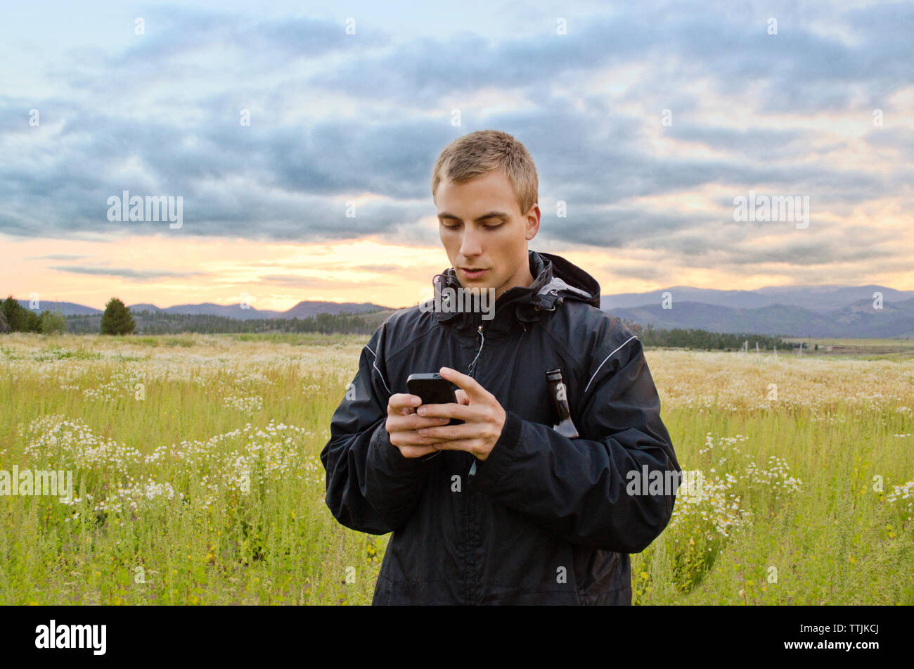 Man using smart phone while standing on field against cloudy sky Stock ...