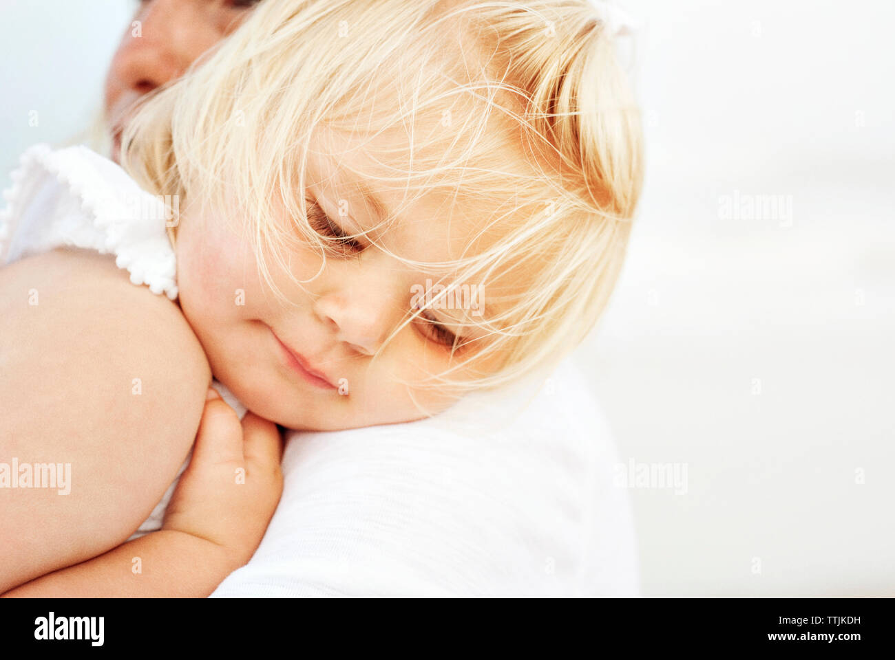 Cute girl leaning on mothers shoulder Stock Photo - Alamy