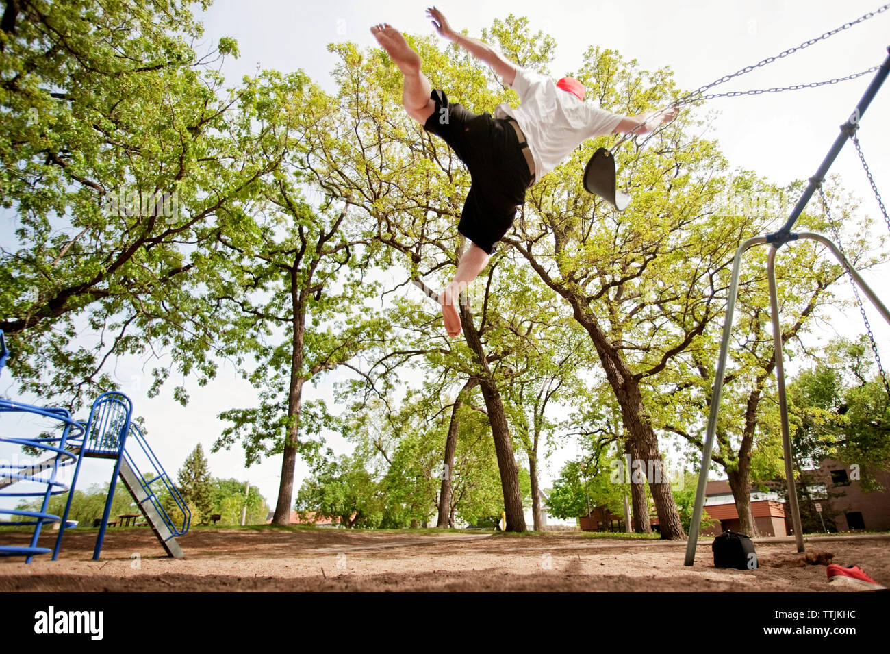 Rear view of man falling from swing at playground Stock Photo - Alamy