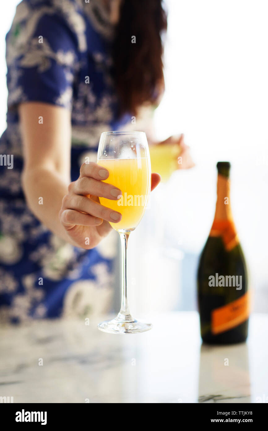 Midsection of woman holding glass of juice while standing at home Stock ...