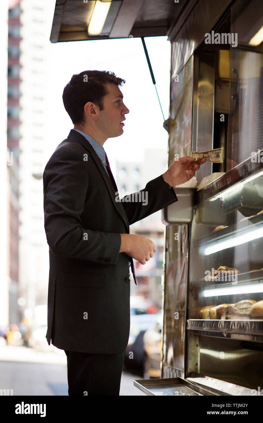 Side view of businessman buying food at stall Stock Photo - Alamy