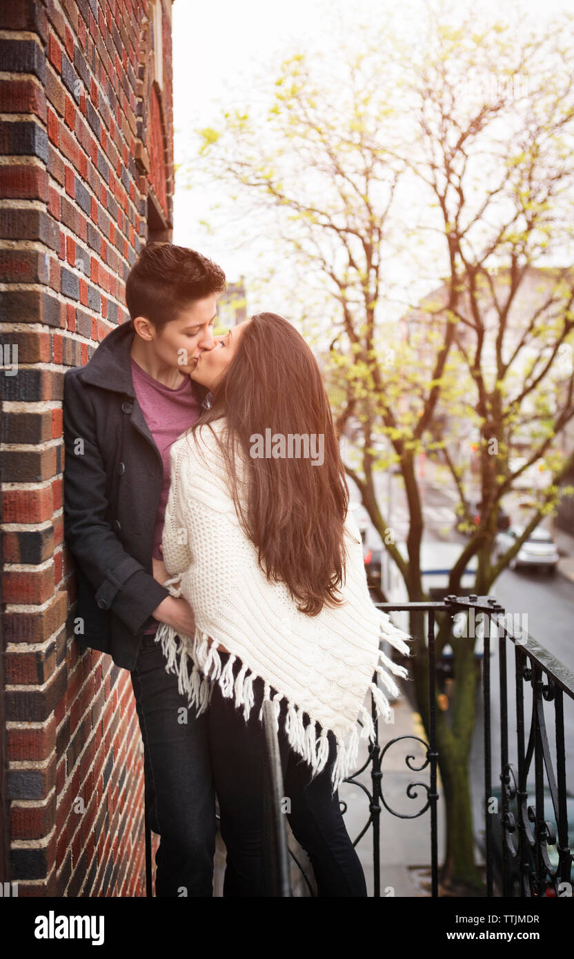 Affectionate Lesbian Couple Kissing While Standing In Balcony Stock